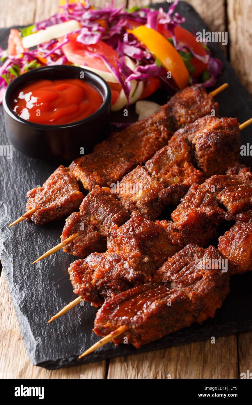 Nigerian spicy suya kebab on skewers with fresh vegetable salad and ...