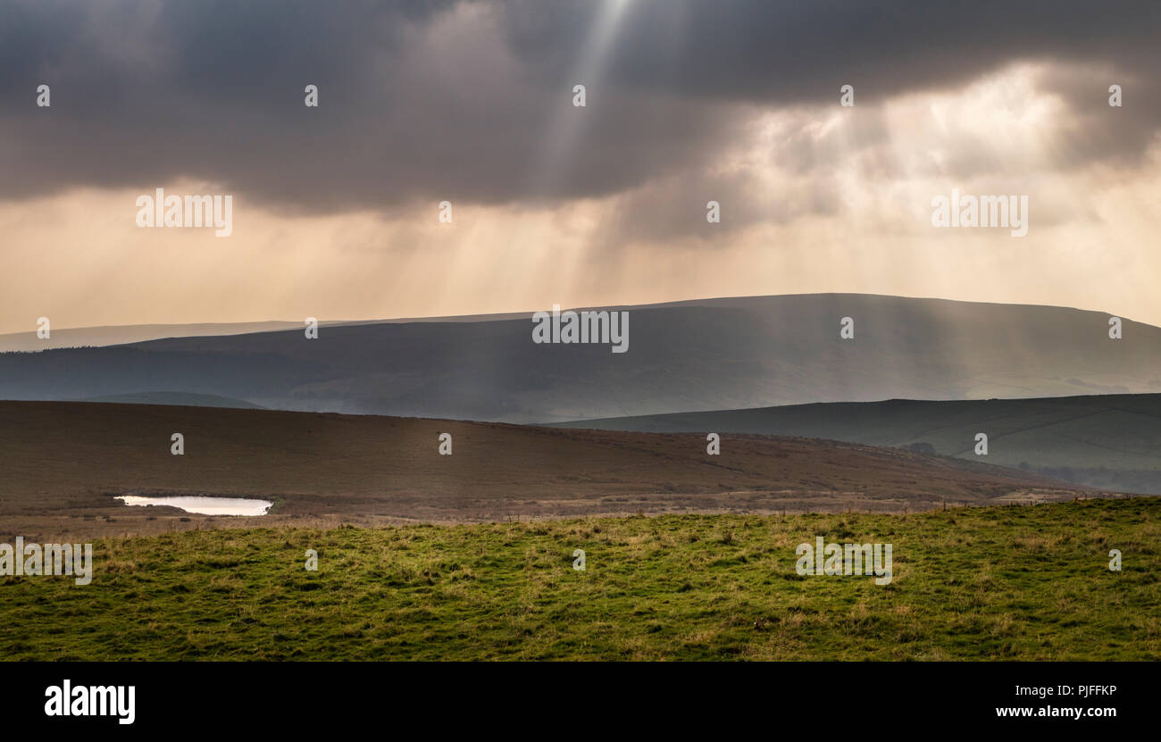 Crepuscular rays of sunlight shine through heavy rain clouds over a ...