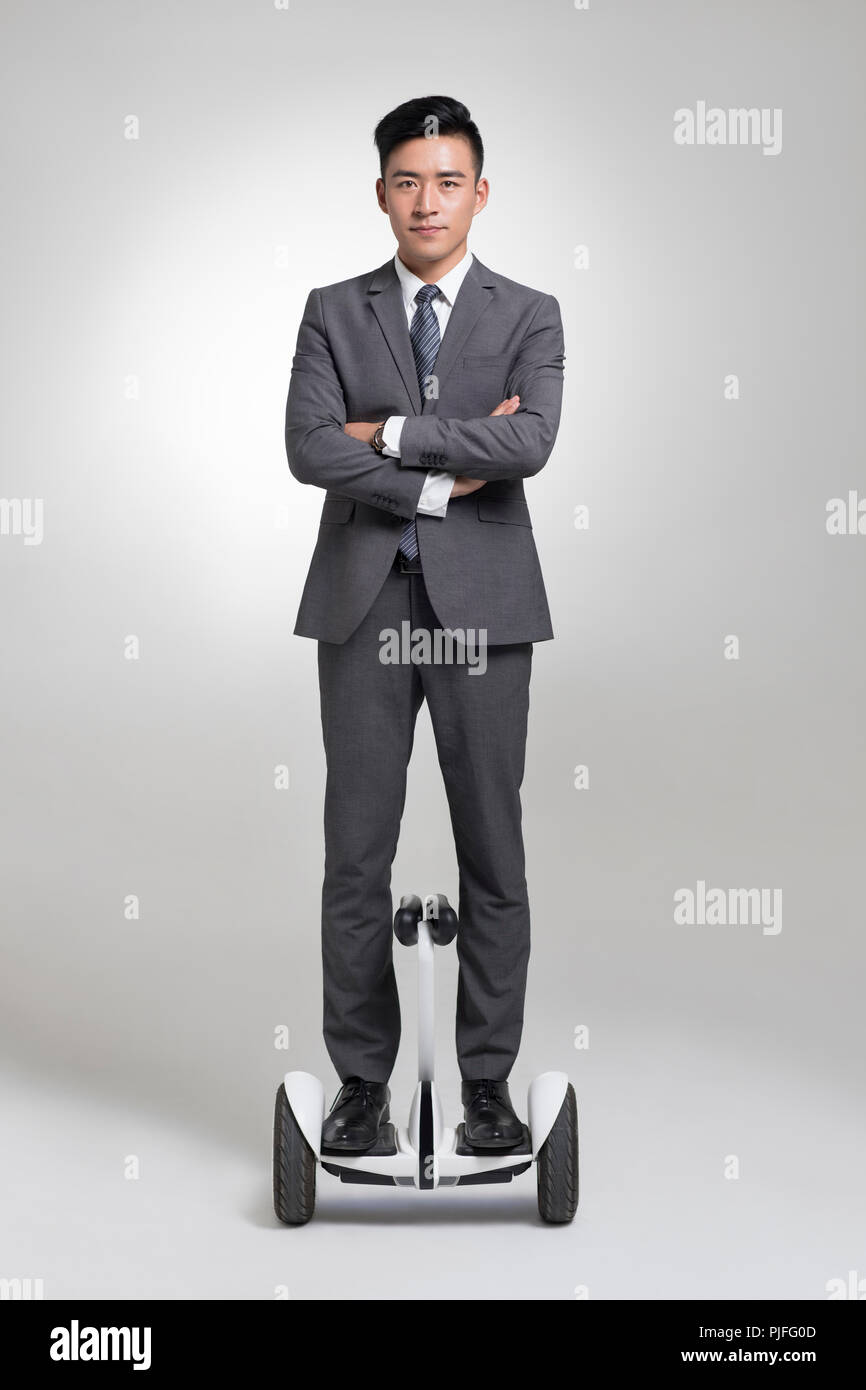 Confident young businessman riding segway Stock Photo - Alamy