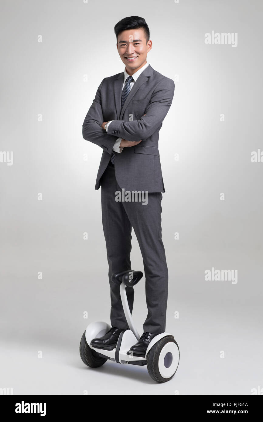 Confident young businessman riding segway Stock Photo - Alamy