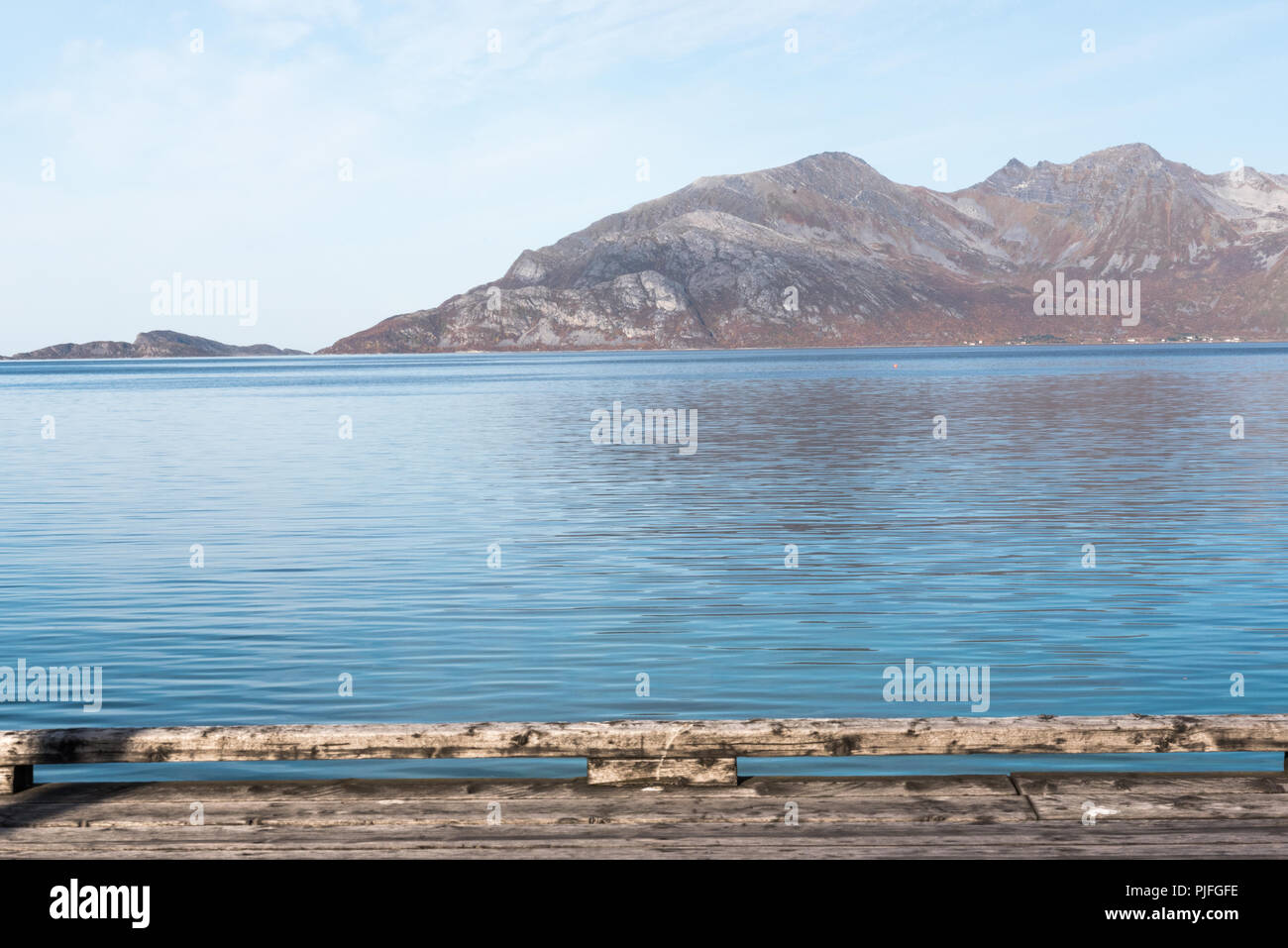 Wooden Boardwalk Jetty Pier with Still Ocean Water with Mountains in ...