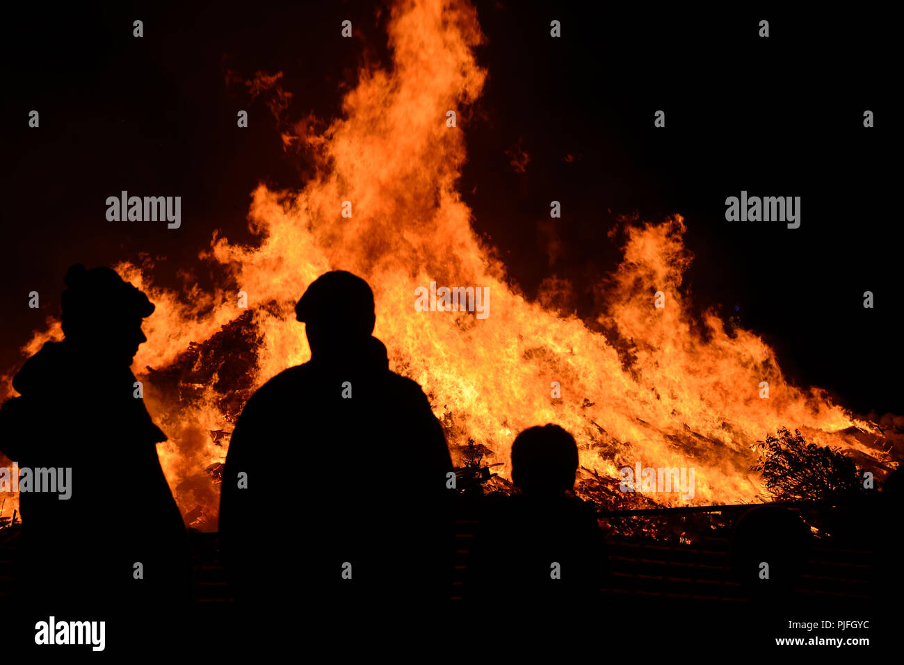 People are silhouetted against the flames of a large bonfire on the 5th ...