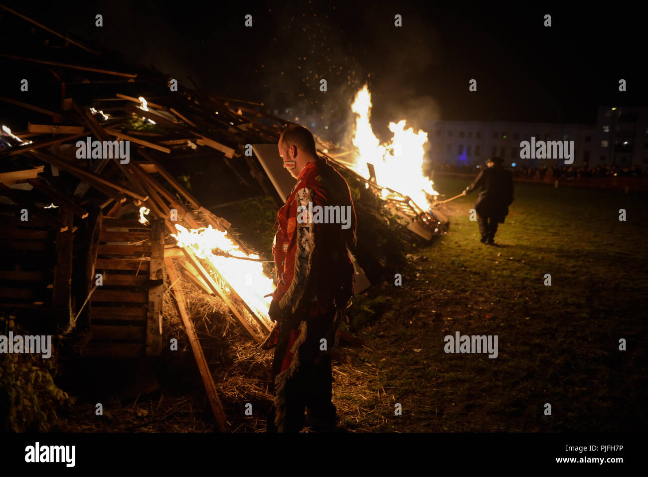 A man lights a large bonfire with a flaming torch during the Bonfire ...