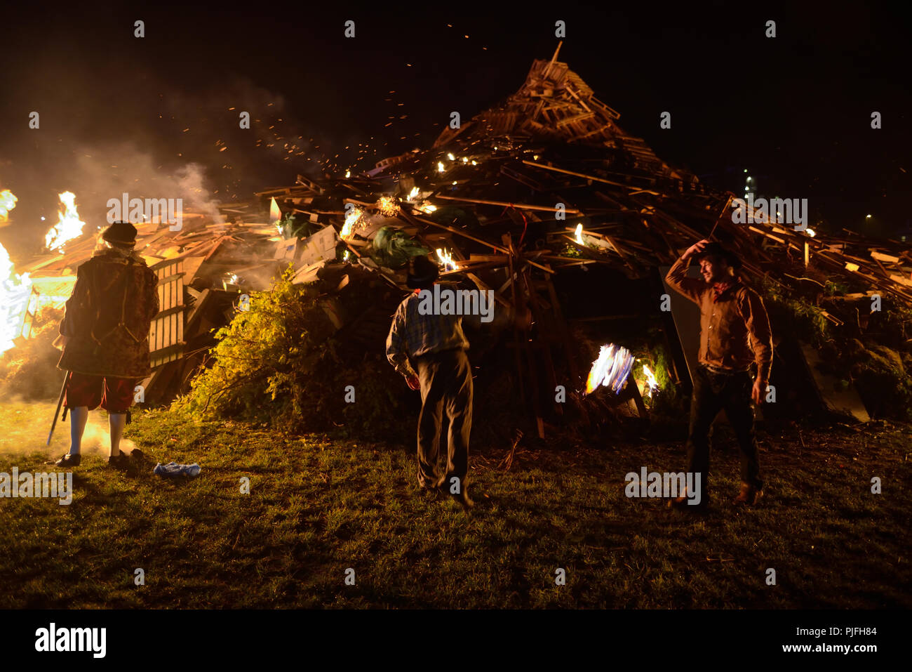 People ignite a bonfire by throwing lit flaming torches on to it during ...