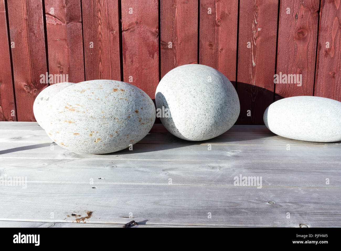 Smooth Round Stones on Wooden Decking against Cladding Stock Photo - Alamy