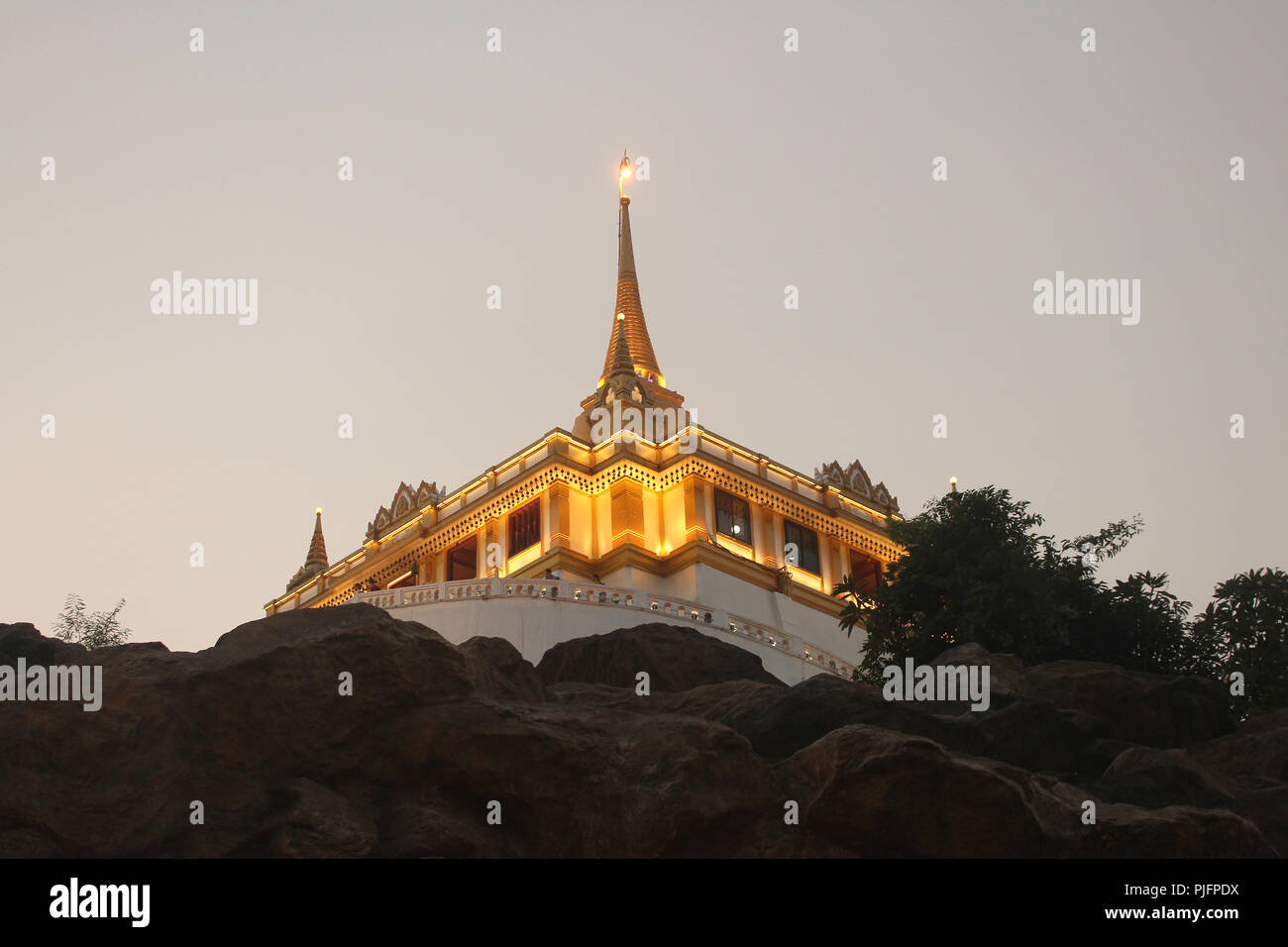 Horizontal bottom view photo of illuminated Golden Mount at dusk, also known as Wat Saket ...