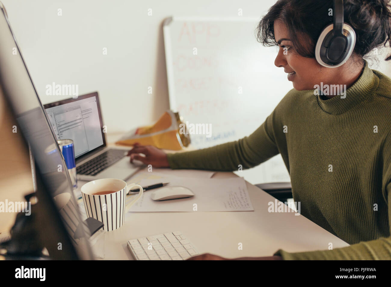 Female programmer working in office. Woman looking at laptop while ... Female programmer working in office. Woman looking at laptop while ...