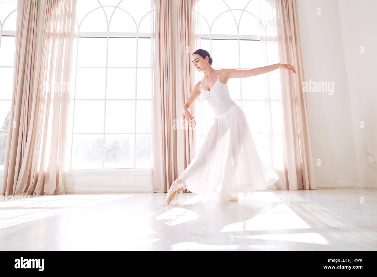 Ballerina dancing in a studio on background window Stock Photo - Alamy