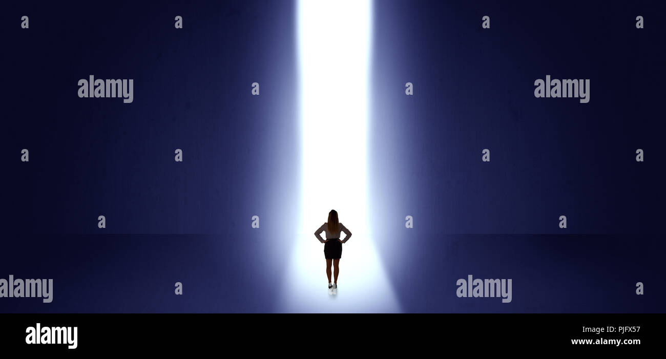 Woman standing and seeing the light at the end of a big wall Stock ...
