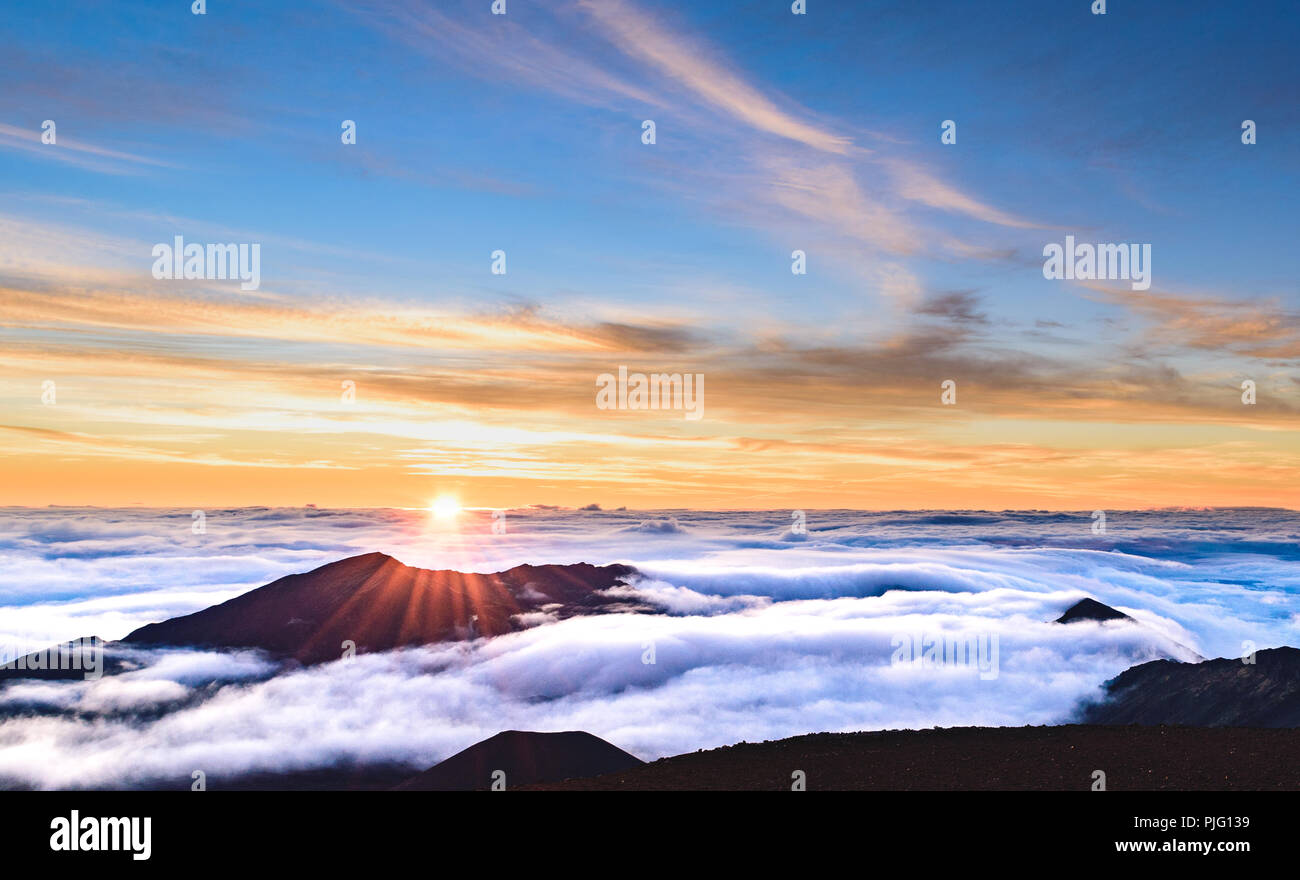 A blazing morning sun slowly rises over a shroud of clouds in the ...