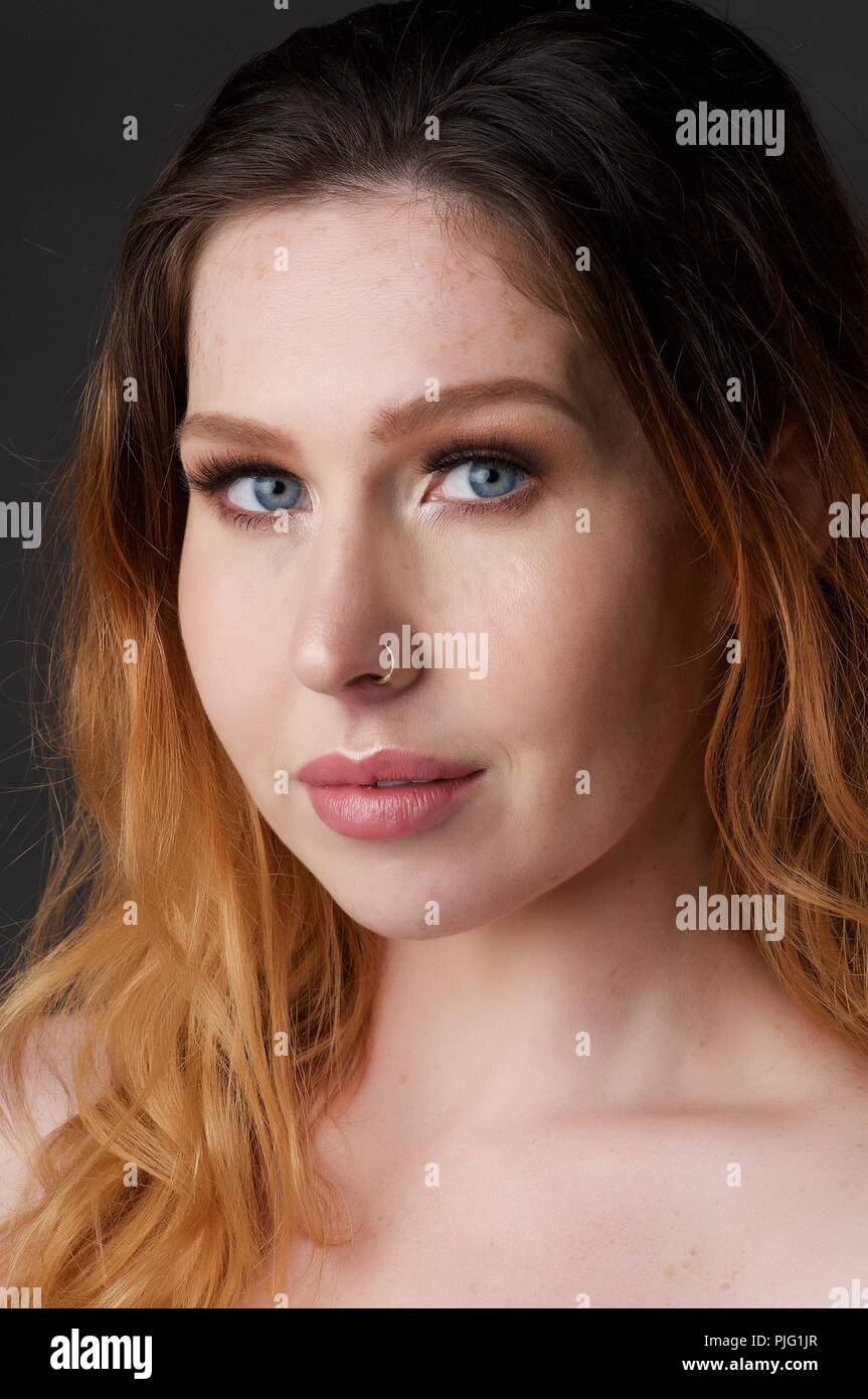Headshot of a red haired girl in the studio against a grey background ...