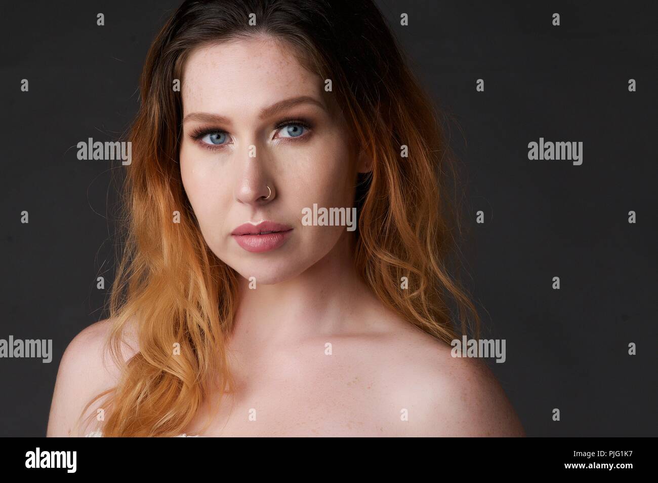 Headshot of a red haired girl in the studio against a grey background ...