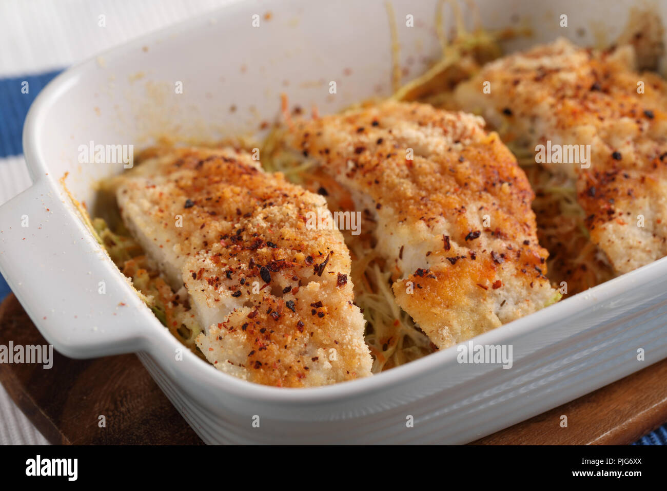 Baked breaded cod fish on vegetable bed Stock Photo - Alamy