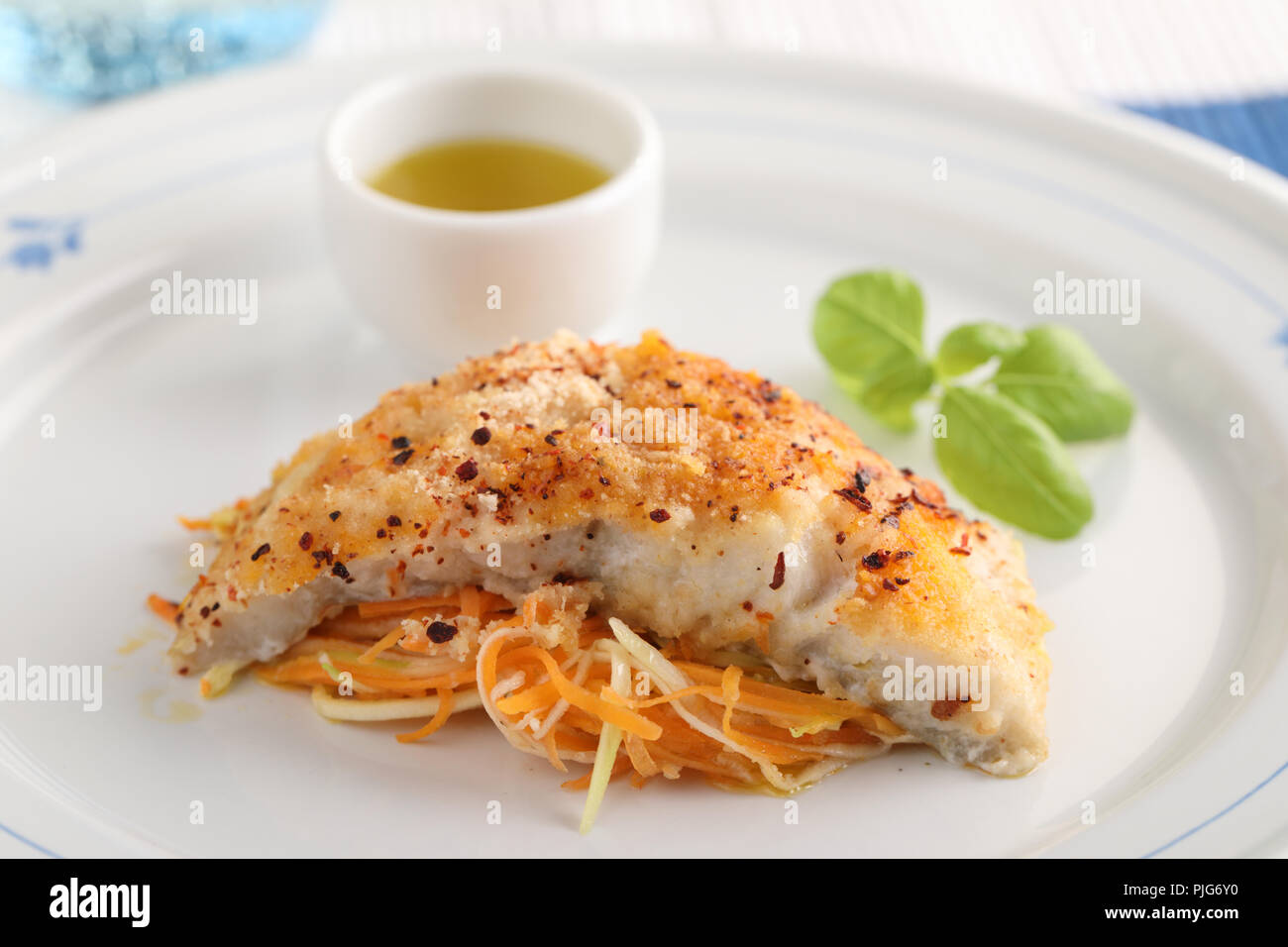 Baked breaded cod fish on vegetable bed topped with basil leaf Stock ...