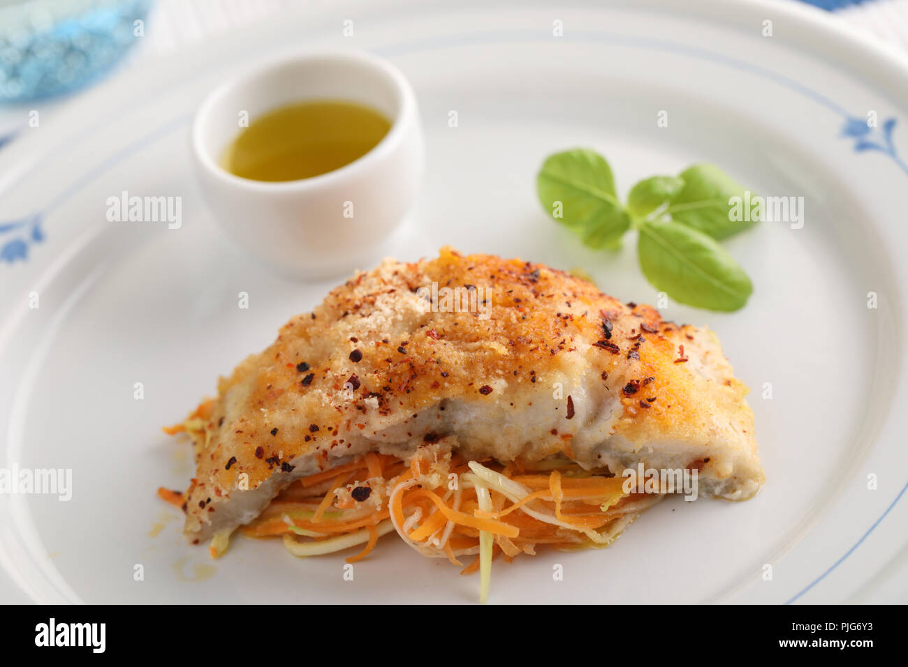 Baked breaded cod fish on vegetable bed topped with basil leaf Stock ...