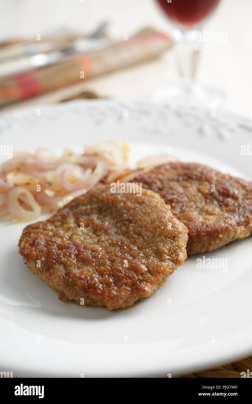 Beef schnitzels with onion on a plate Stock Photo - Alamy