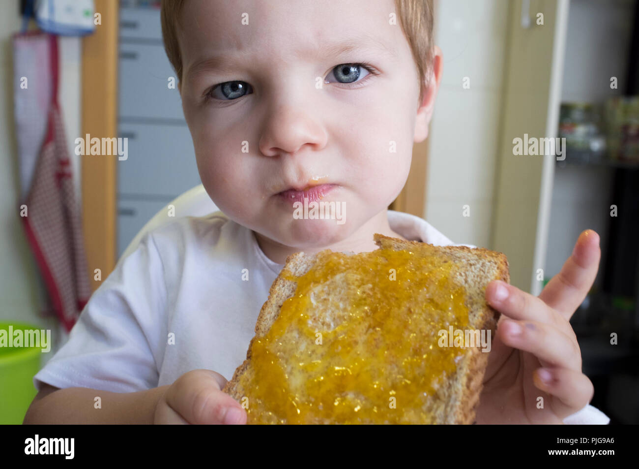 Little baby boy eating peach jam toast. Closeup Stock Photo - Alamy