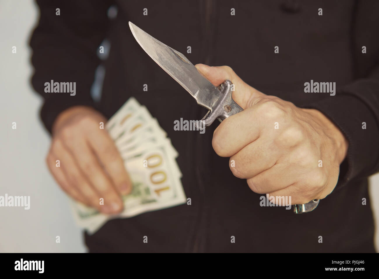 Robber with knife in hand and American money. bandit pulls out his ...