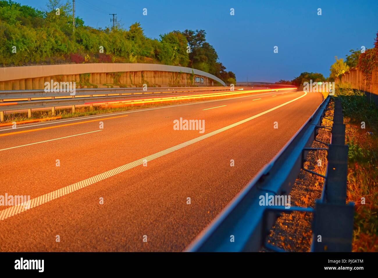 Highway at twilight with light trails. High traffic road with ...