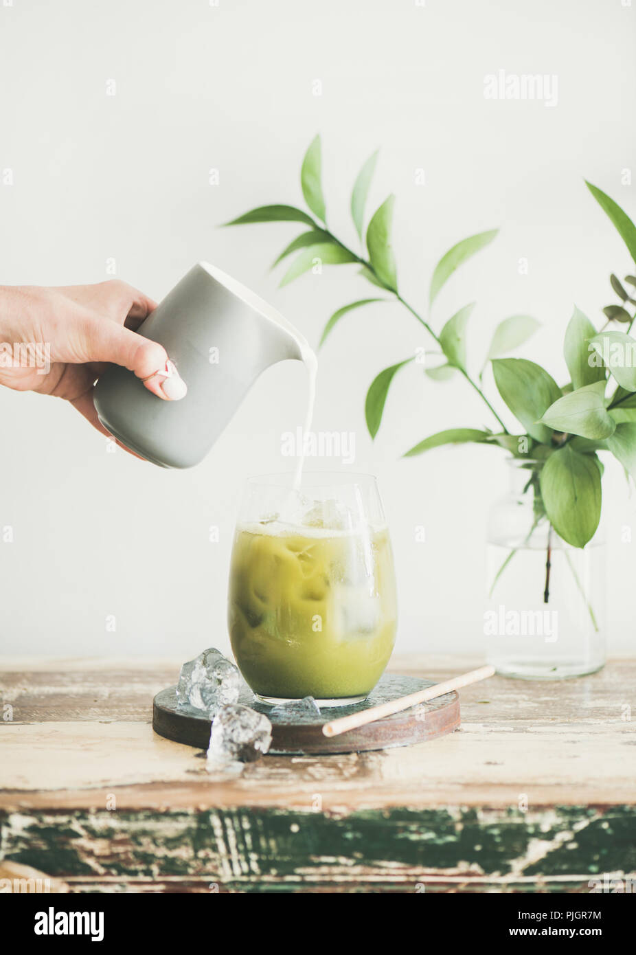 Iced matcha latte drink in tumbler glass on board with coconut milk ...
