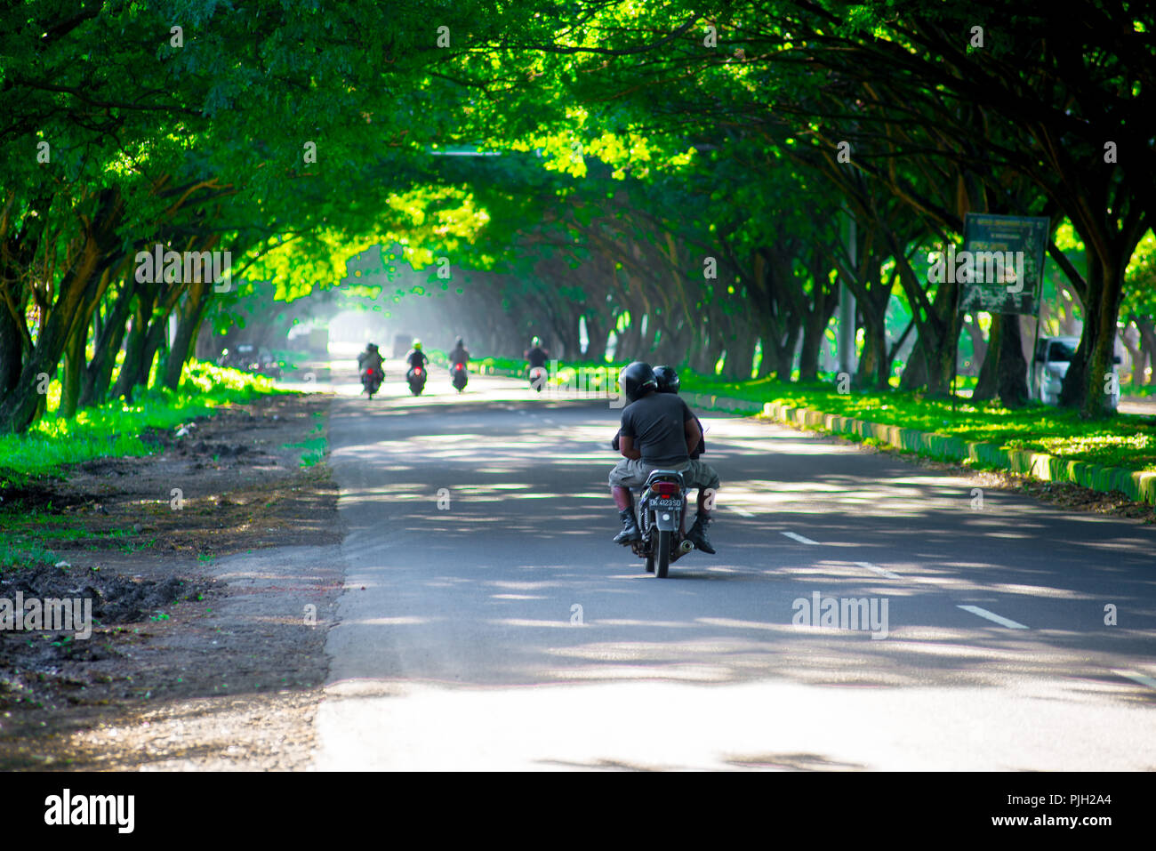 Indonesian men riding bikes in Bali, Indonesia. Jakarta is the biggest ...