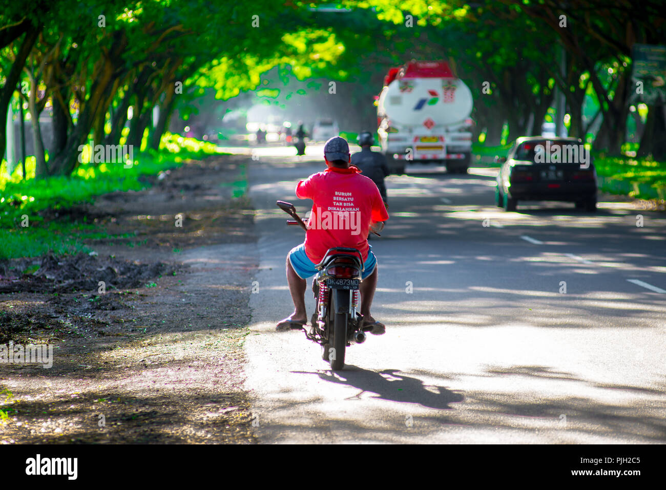 Indonesian men riding bikes in Bali, Indonesia. Jakarta is the biggest ...