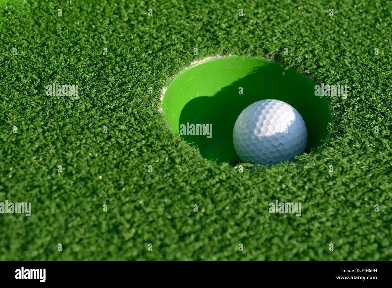 Minigolf ball in a hole closeup Stock Photo - Alamy