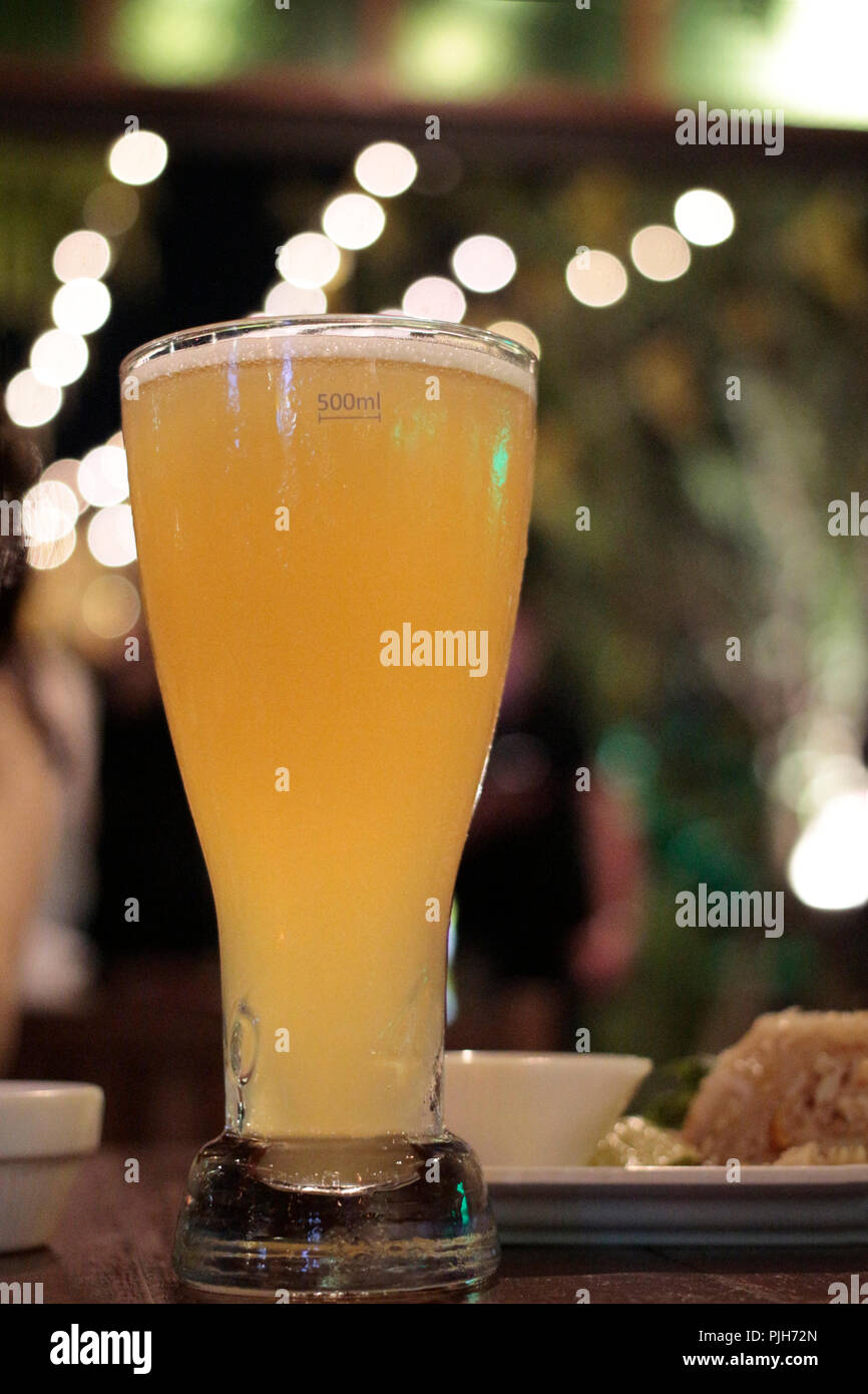 a glass of pilsner beer put on the table with some food in a restaurant ...