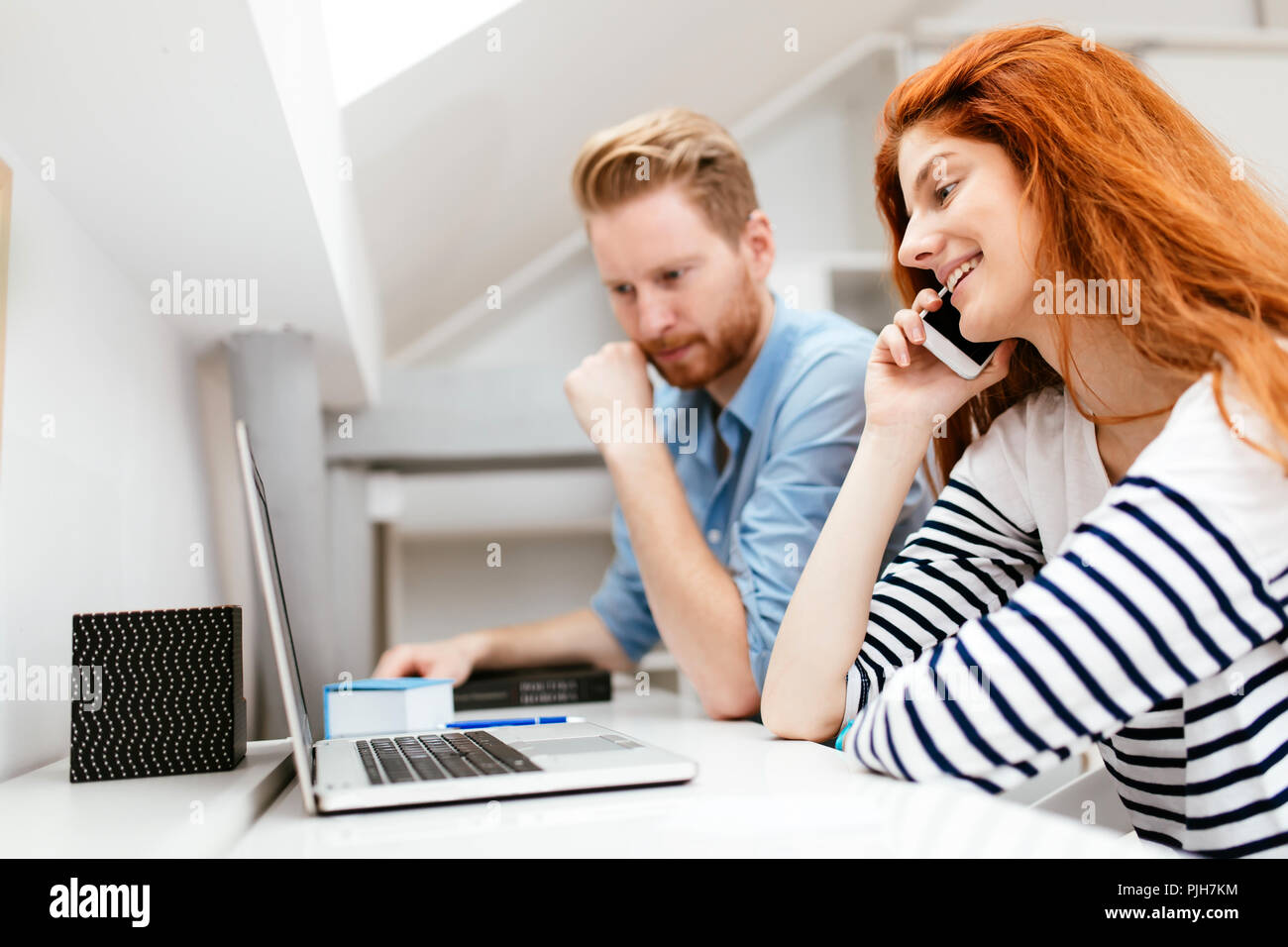 Beautiful ginger woman working in office with colleague Stock Photo - Alamy