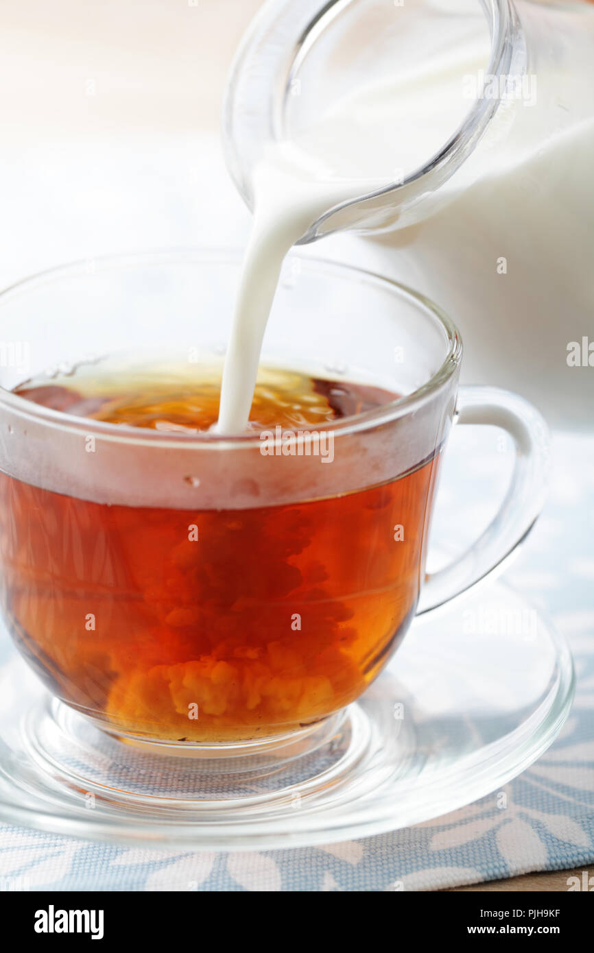 Pouring milk into cup with tea Stock Photo - Alamy