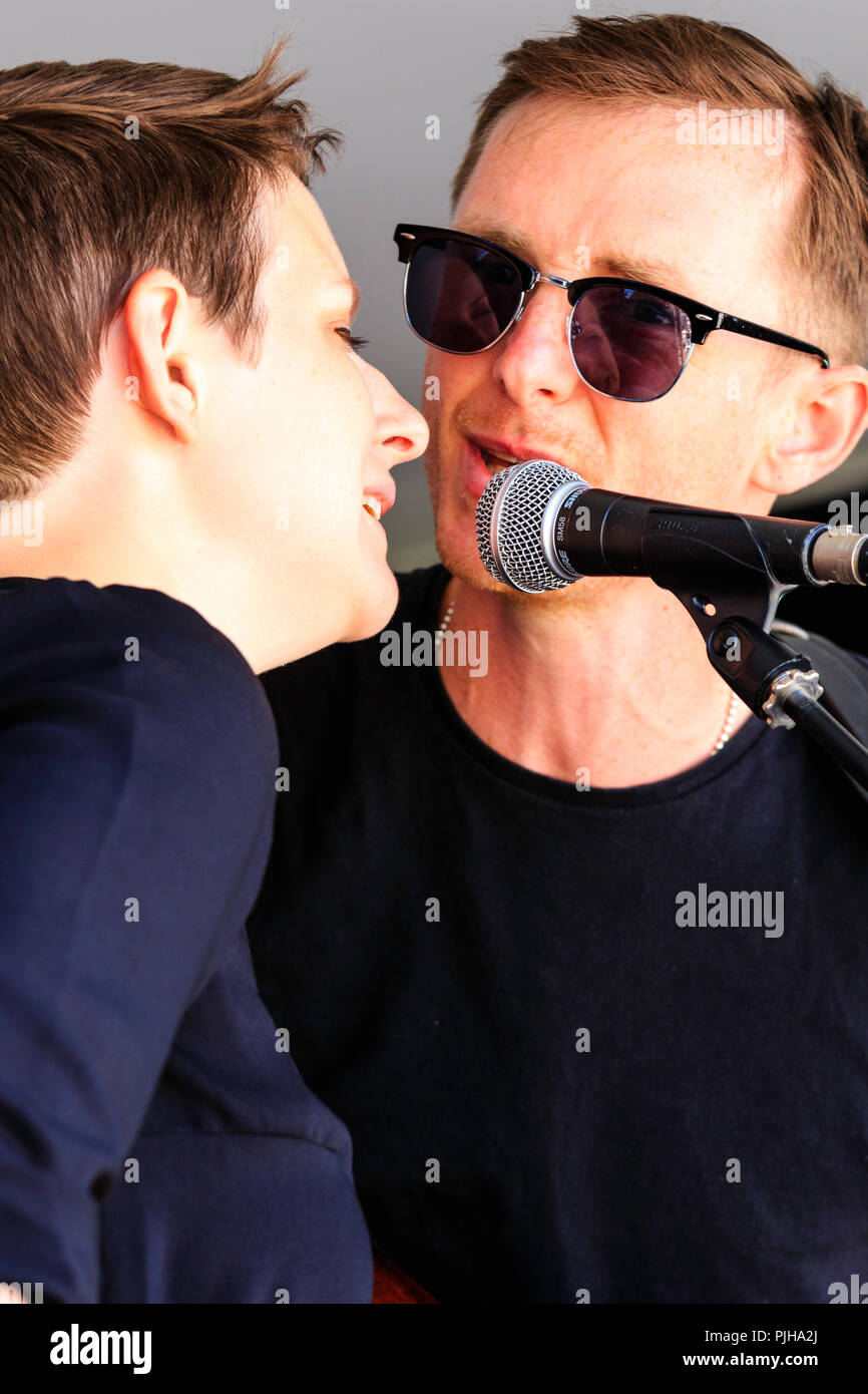 Trevor Moss and Hannah-Lou singing into microphone together and playing ...