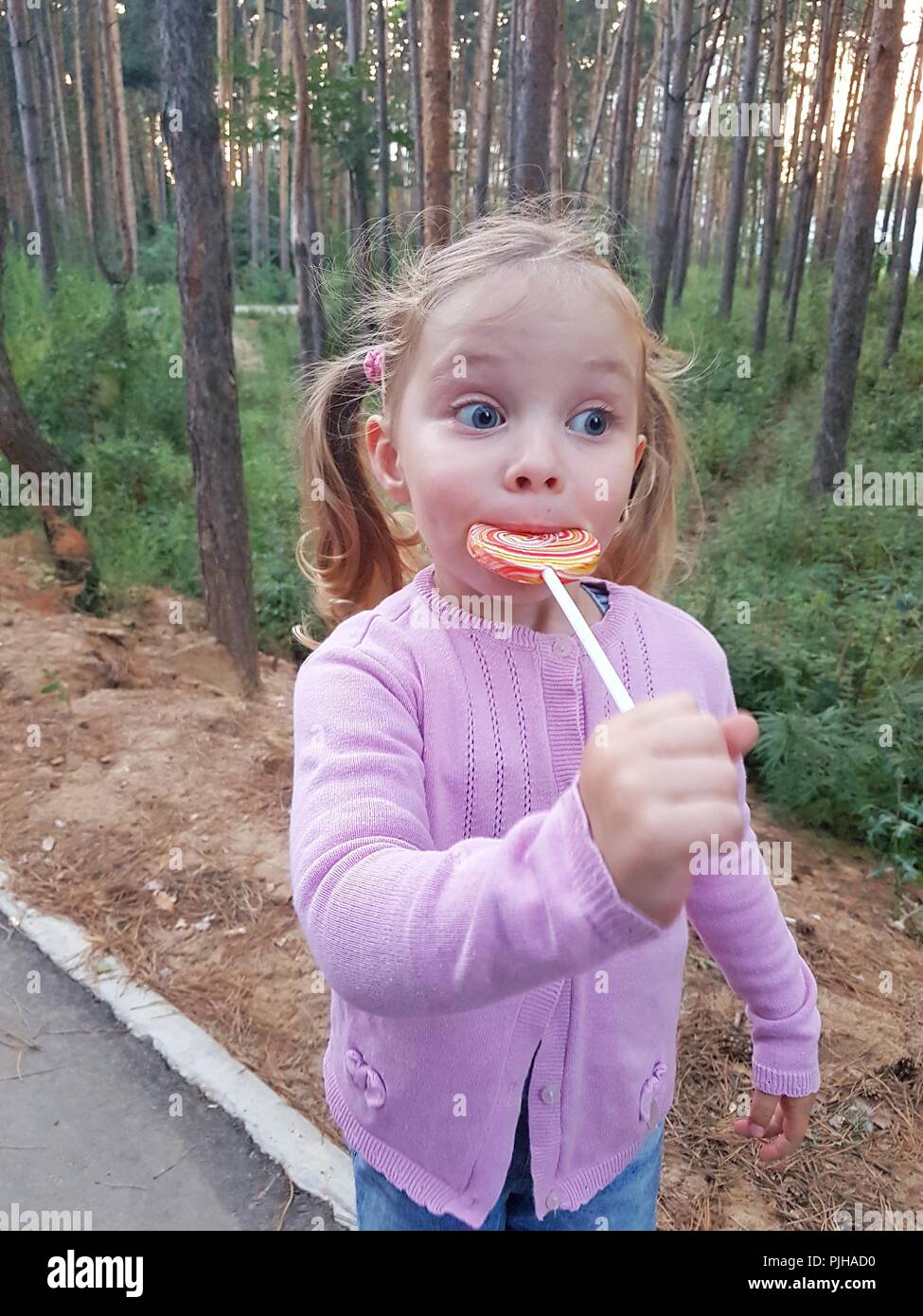 Funny child with candy lollipop, happy little girl eating big sugar ...