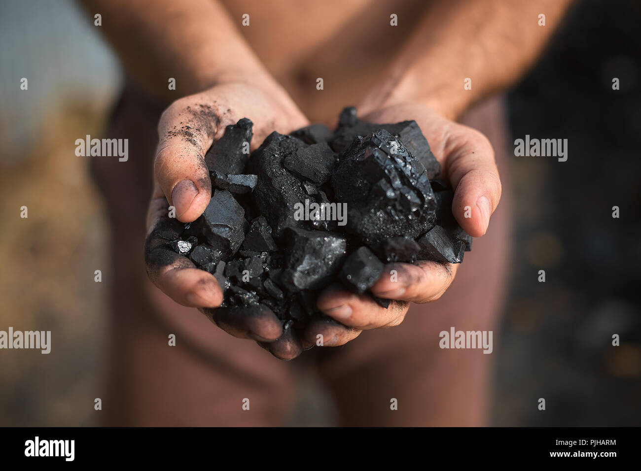poor middle-aged man holding the hands of stone coal for sale to ...