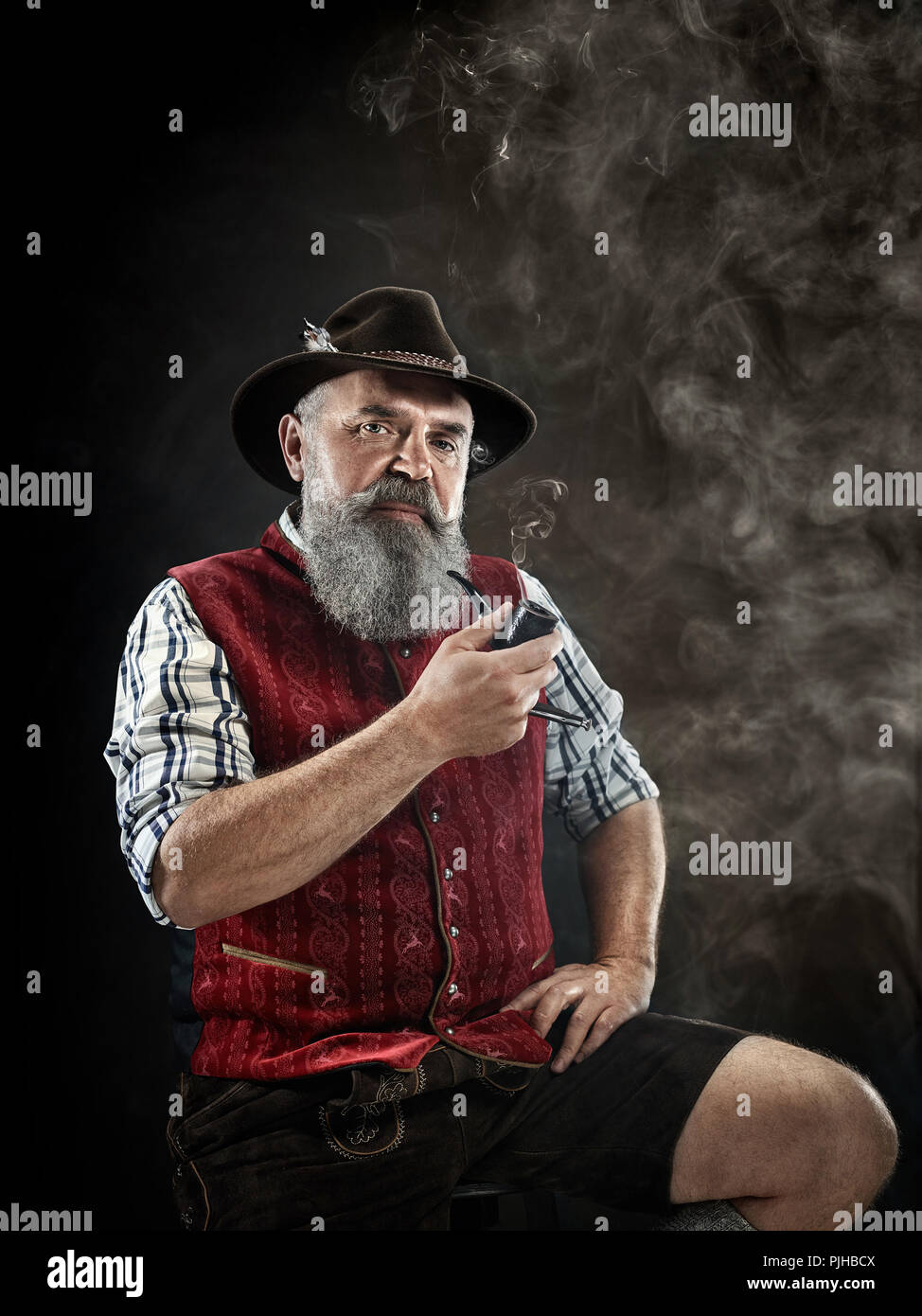 dramatic portrait of gray bearded senior man in hat smoking tobacco ...