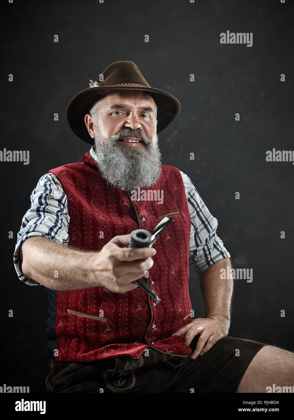 dramatic portrait of gray bearded smiling senior man in hat smoking ...