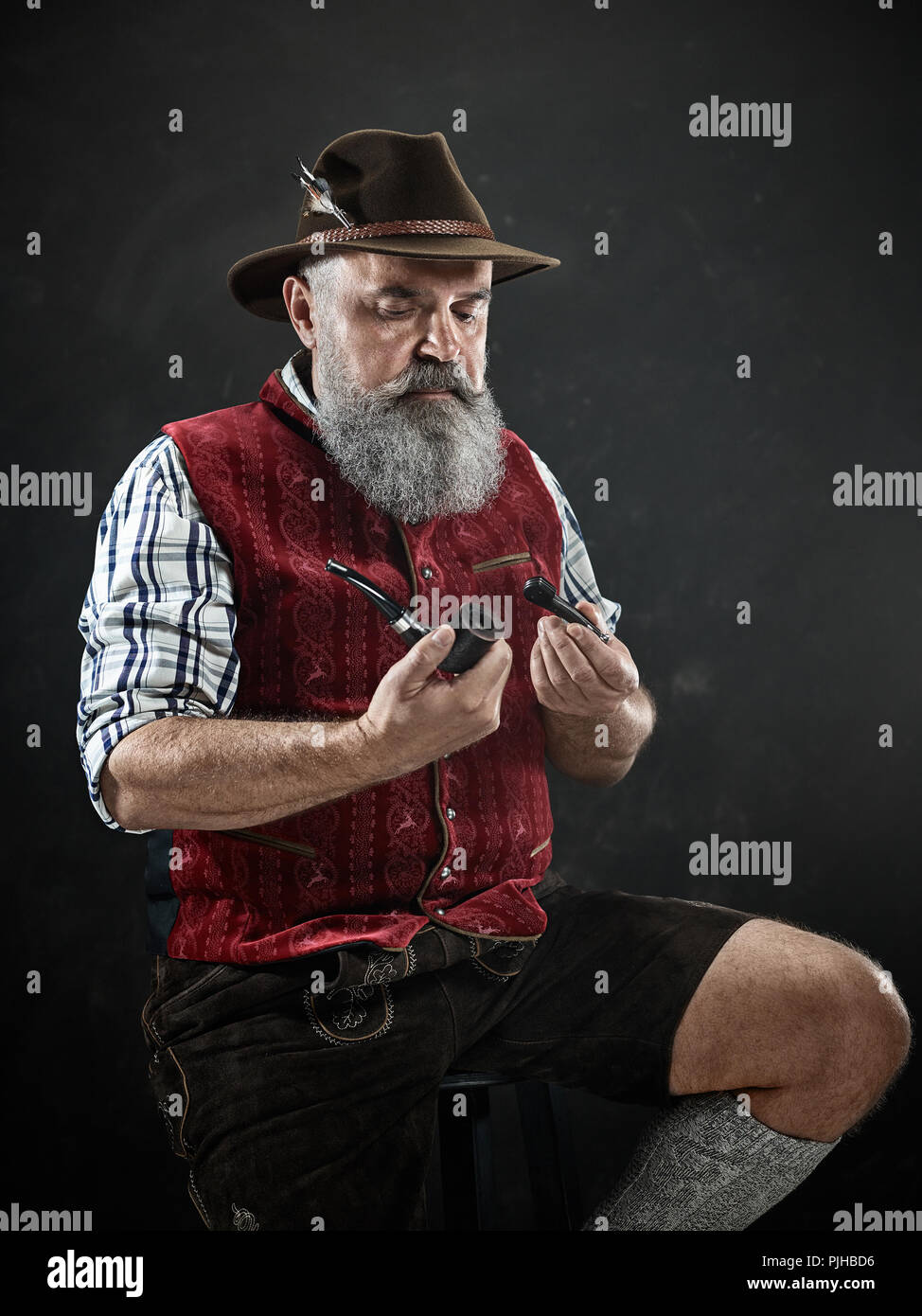 dramatic portrait of gray bearded senior man in hat smoking tobacco ...
