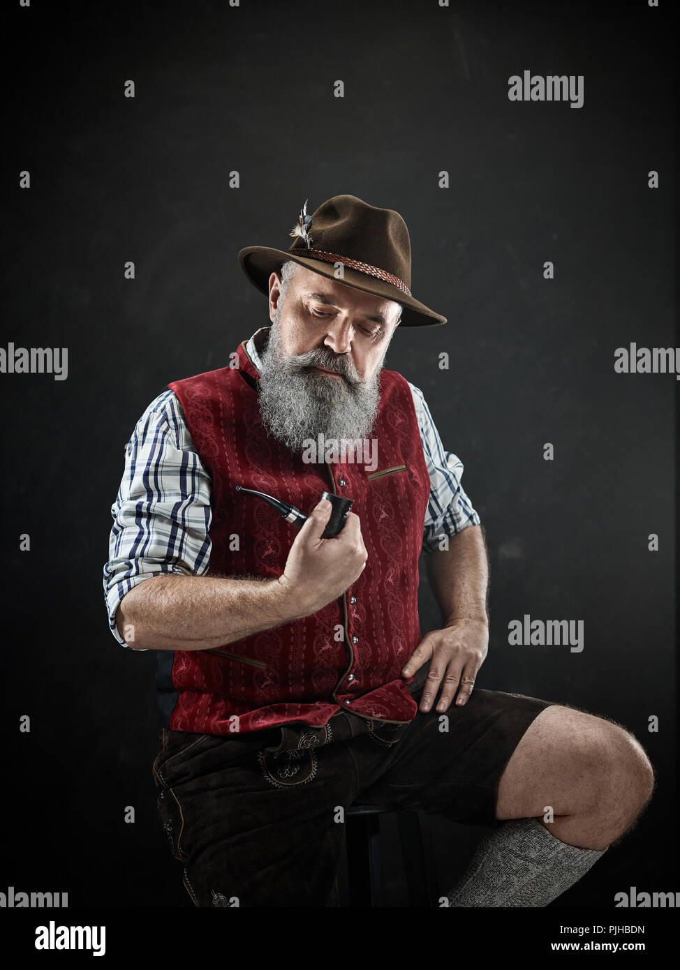 dramatic portrait of gray bearded senior man in hat smoking tobacco ...