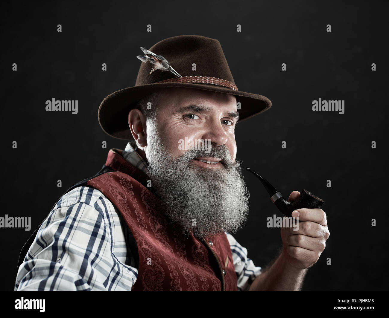 dramatic portrait of gray bearded senior man in hat smoking tobacco ...