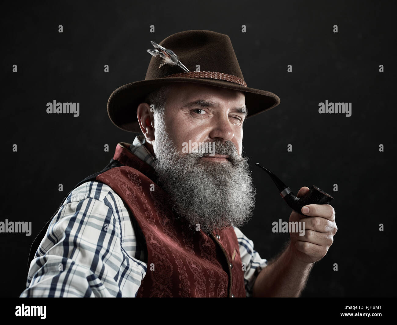dramatic portrait of gray bearded senior man in hat smoking tobacco ...