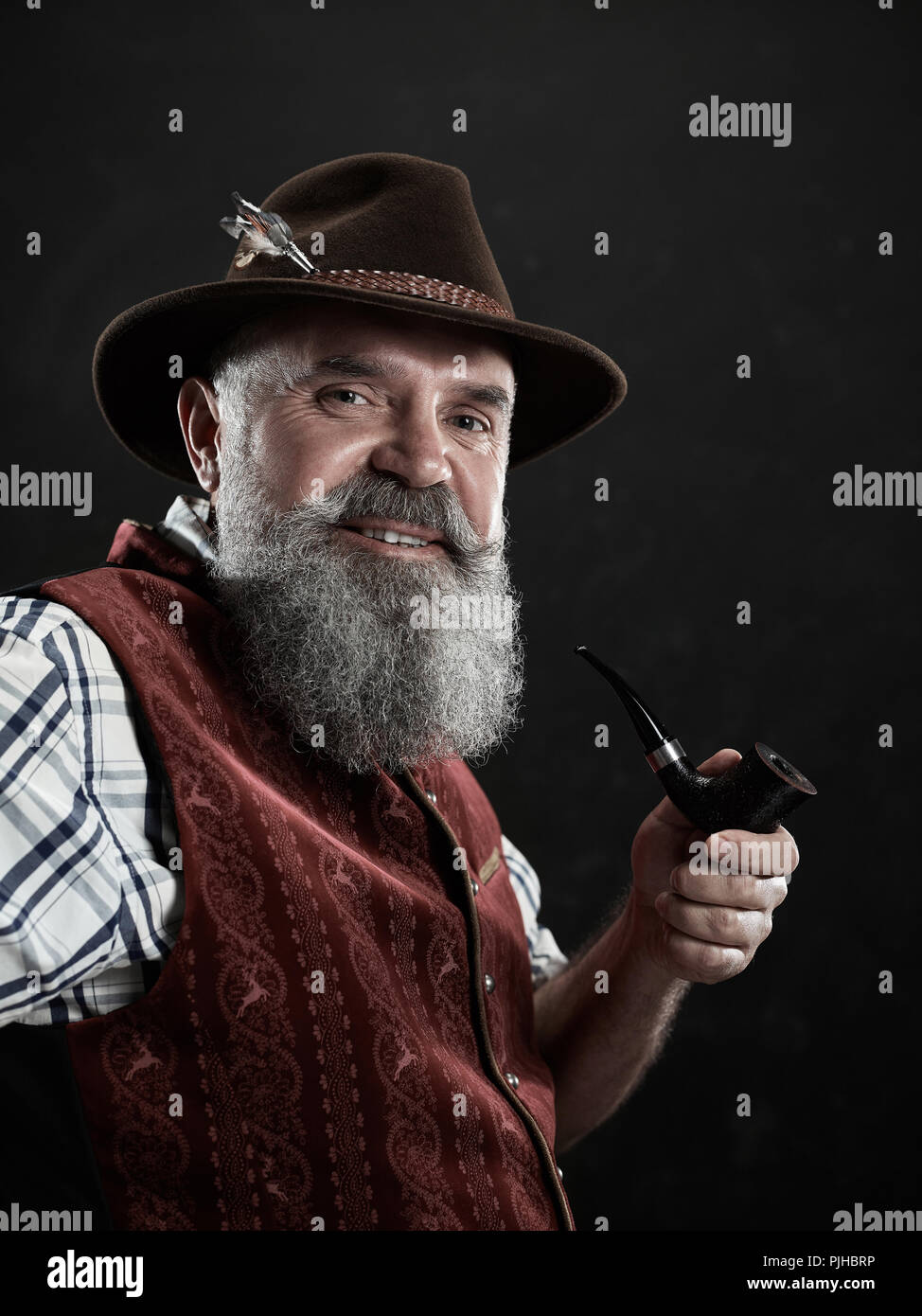 dramatic portrait of gray bearded smiling senior man in hat smoking ...