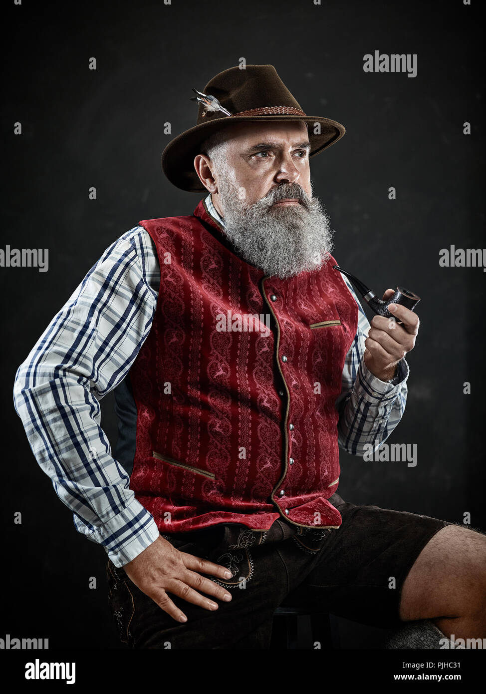 dramatic portrait of gray bearded senior man in hat smoking tobacco ...
