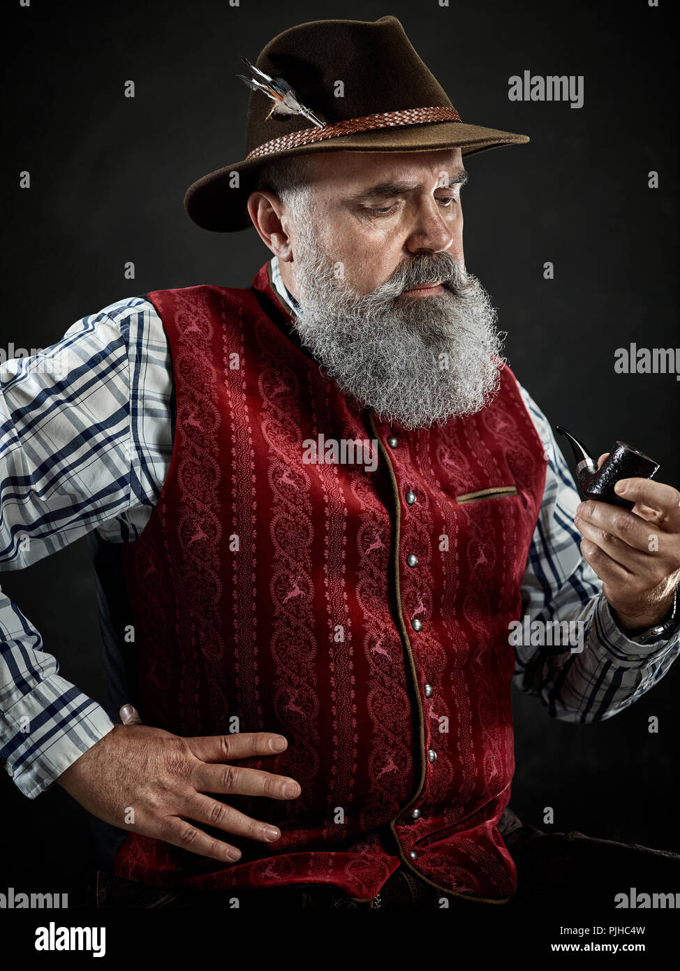 dramatic portrait of gray bearded senior man in hat smoking tobacco ...