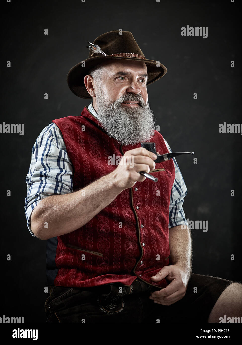dramatic portrait of gray bearded senior man in hat smoking tobacco ...