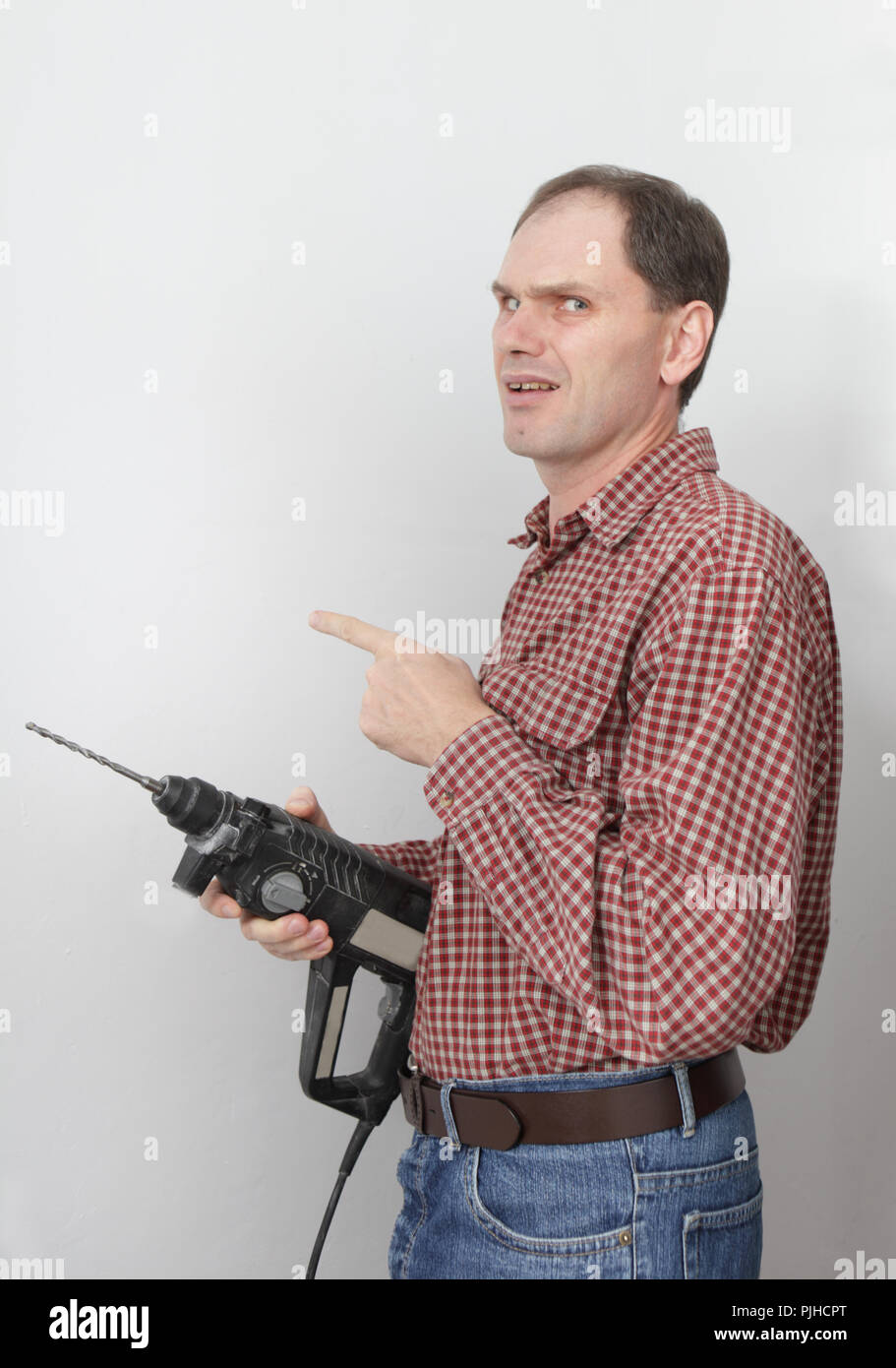 Construction worker with power drill in doubt Stock Photo - Alamy