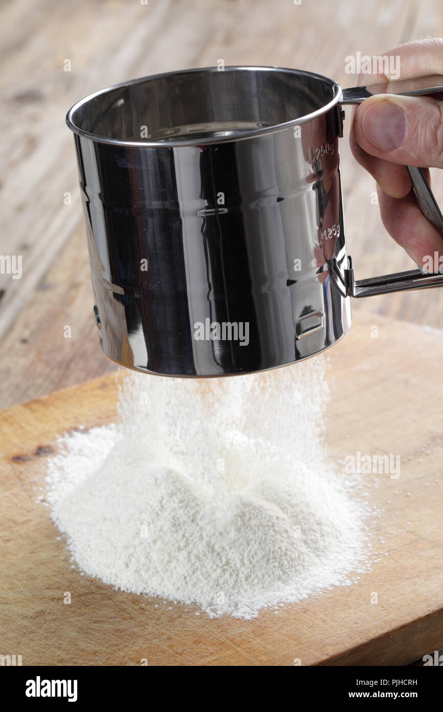 Sieving the flour using the steel sifter Stock Photo - Alamy