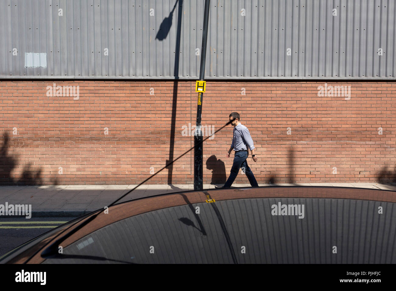 An urban landscape of a leaning lamp post and a vehicle's radio aerial ...