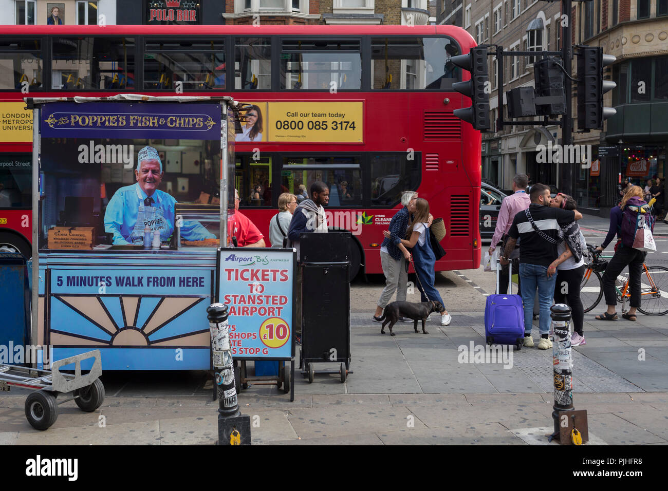A couple kiss and some friends hug near the rear of a newspaper vendor ...