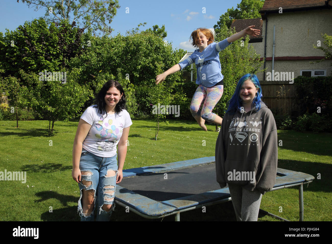 Sisters in garden youngest jumping On trampoline Surrey England Stock ...