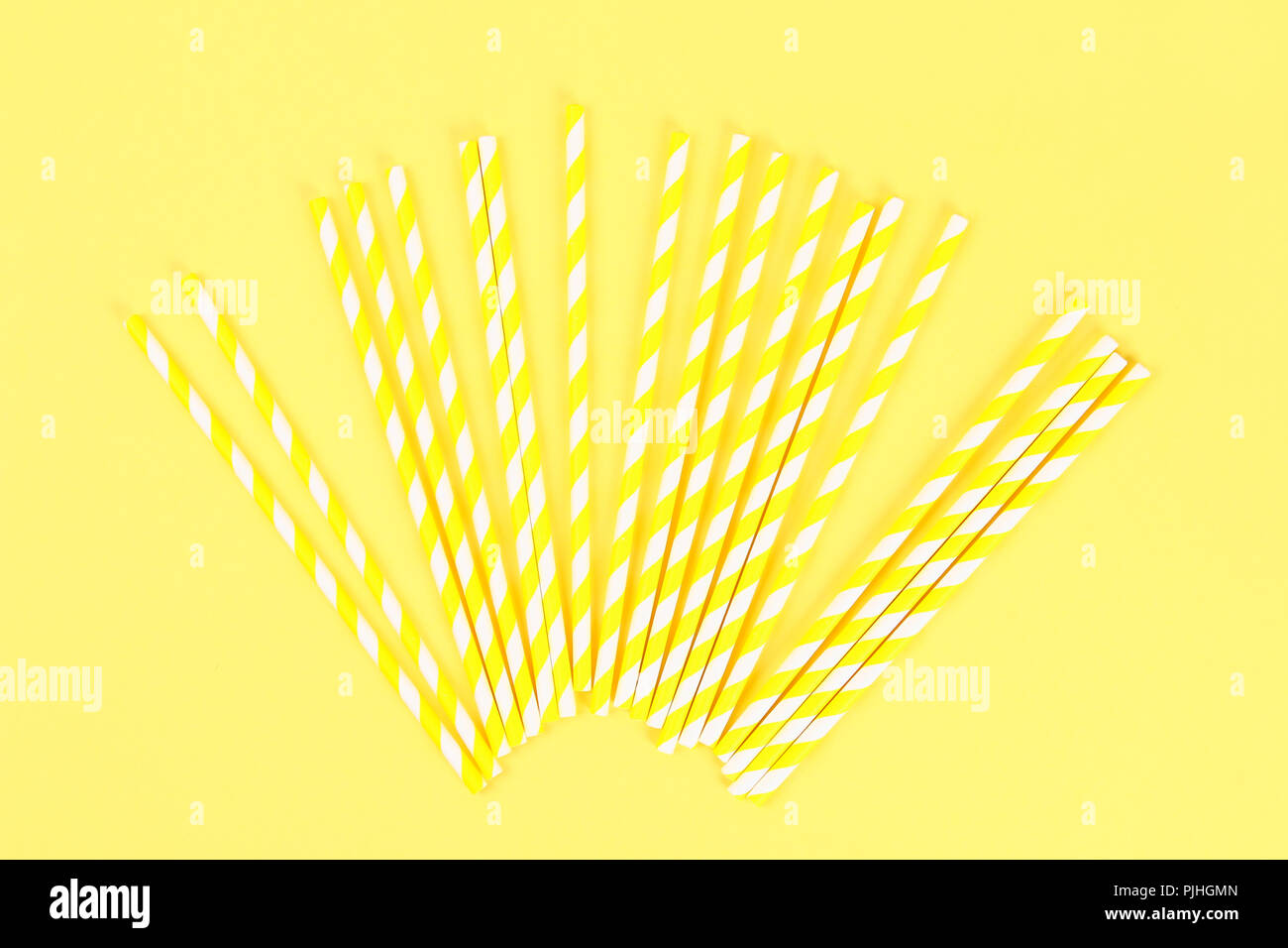 Yellow striped straw paper tubes on a bright yellow pastel background ...