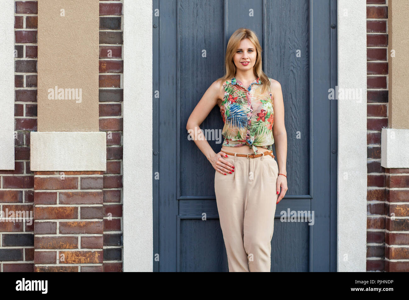 Young beautiful woman in tropical shirt and beige galligaskins standing ...
